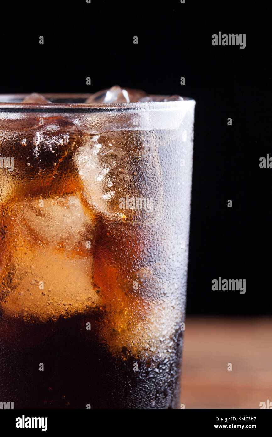 Close up on a cold refreshing soft drink with ice on a dark wooden ...