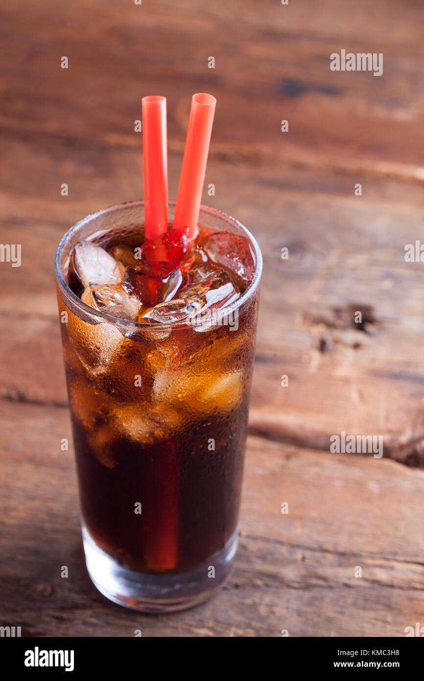 Close up on a cold refreshing soft drink with ice on a dark wooden ...