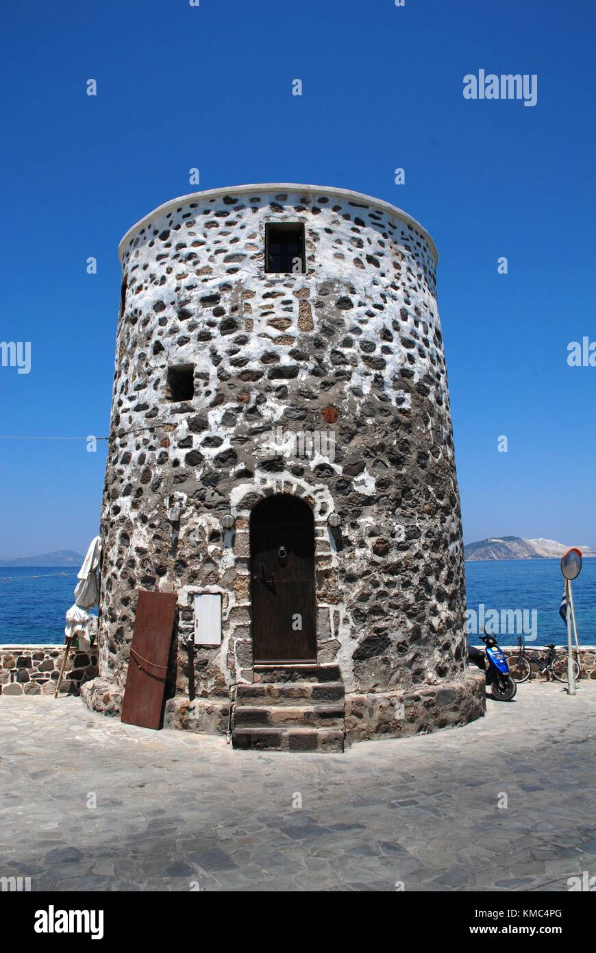An old stone tower on the seafront at Mandraki on the Greek island of ...