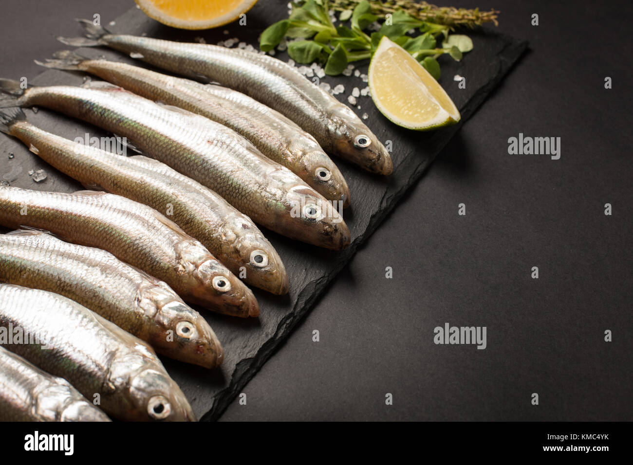 Fresh sea fish smelt or sardines ready for cooking with lemon, thyme ...