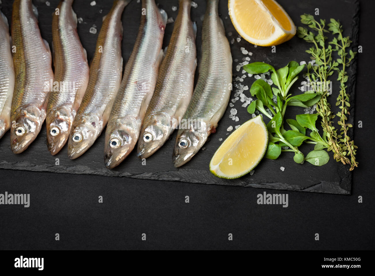 Fresh sea fish smelt or sardines ready for cooking with lemon, thyme ...