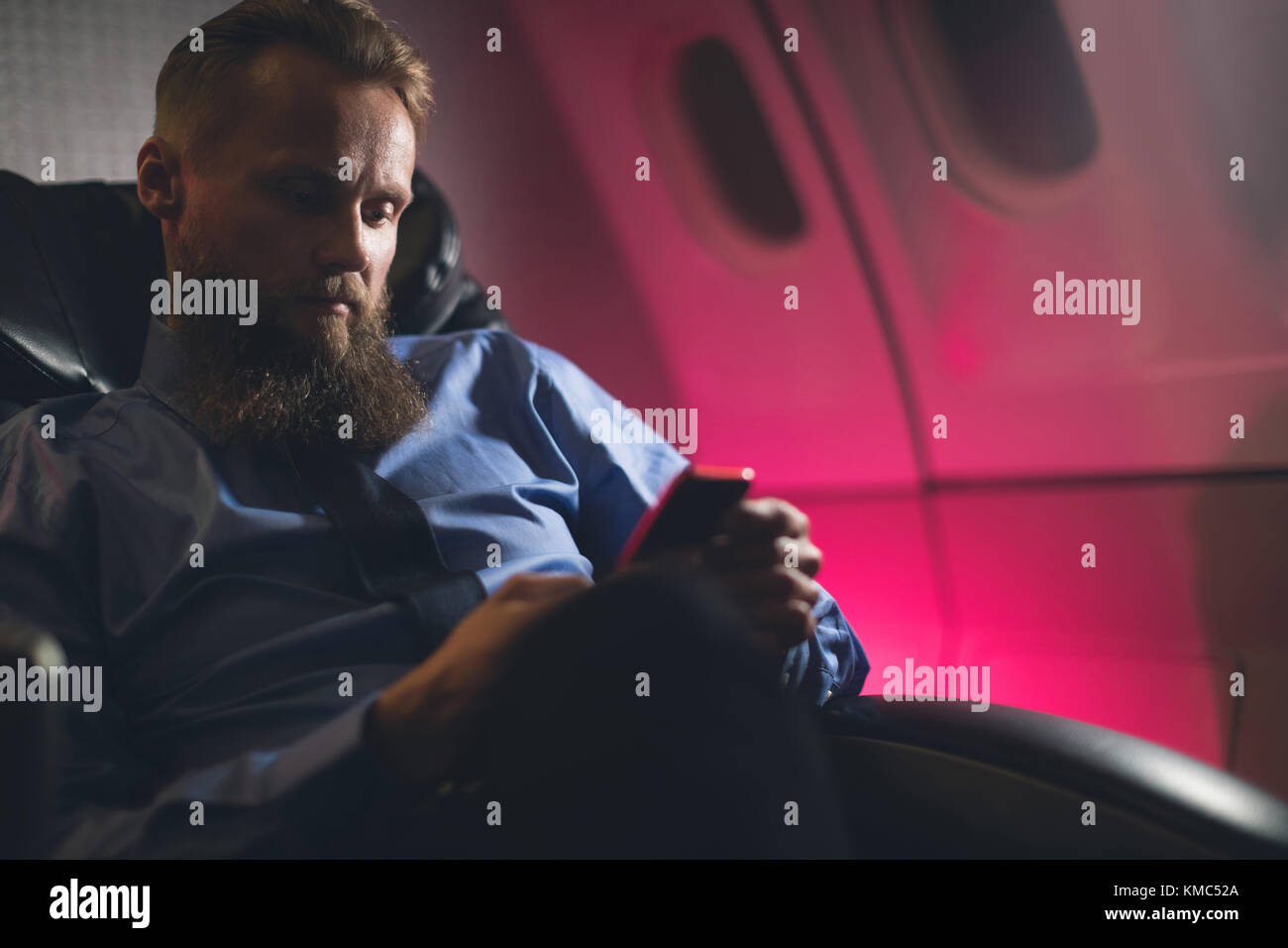 Businessman using mobile phone while travelling in airplane Stock Photo ...