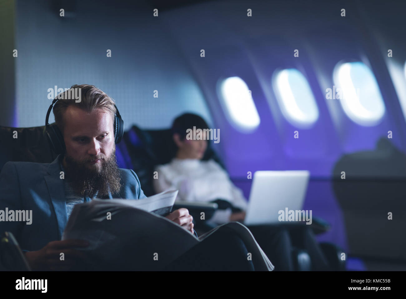 Businessman reading newspaper in airplane Stock Photo - Alamy