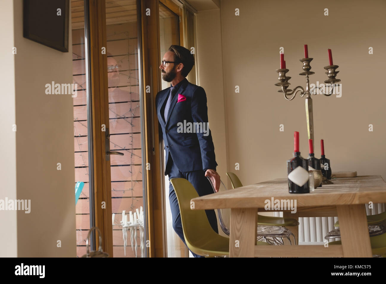 Man in full suit looking through window Stock Photo - Alamy