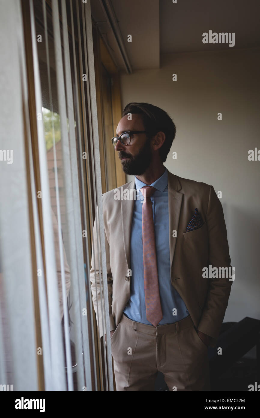 Man in full suit looking through window Stock Photo - Alamy