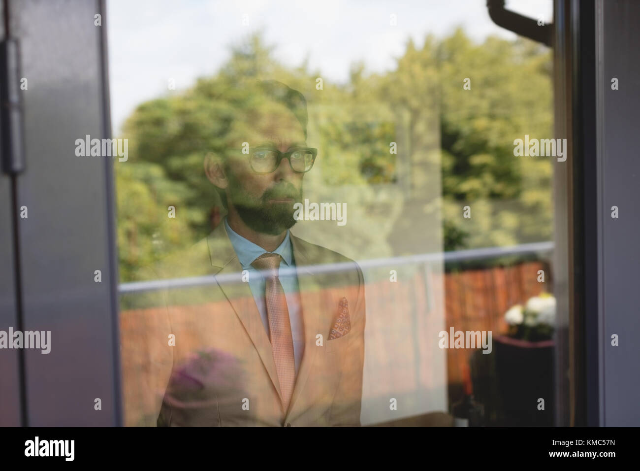 Man in full suit looking through window Stock Photo - Alamy