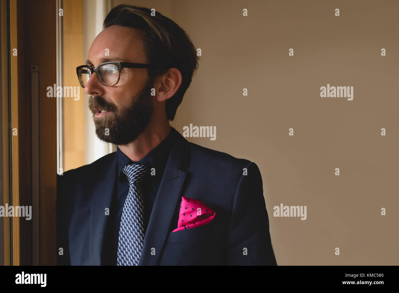 Man in full suit looking through window Stock Photo - Alamy