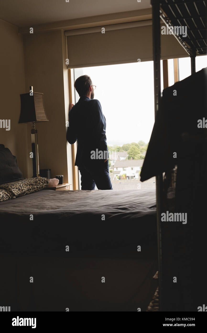 Man in full suit looking through window Stock Photo - Alamy