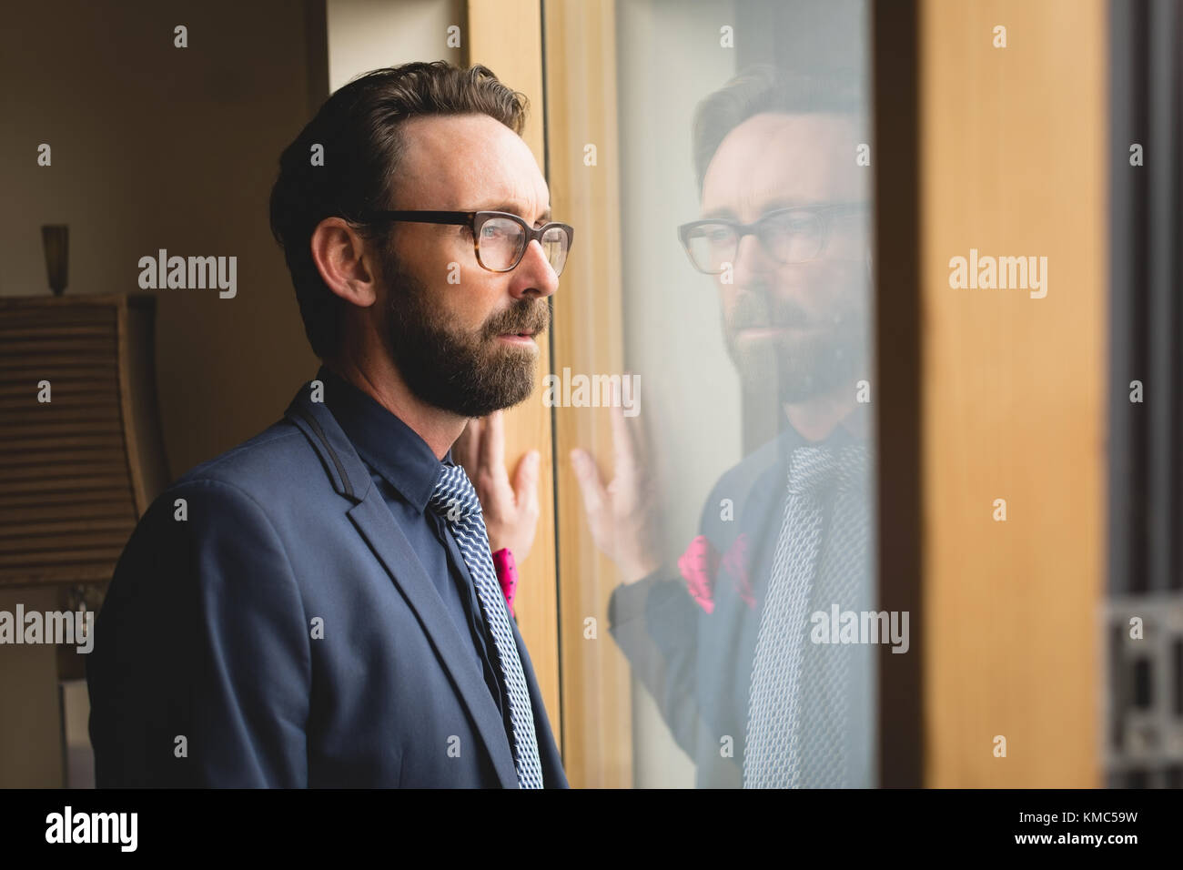 Man in full suit looking through window Stock Photo - Alamy