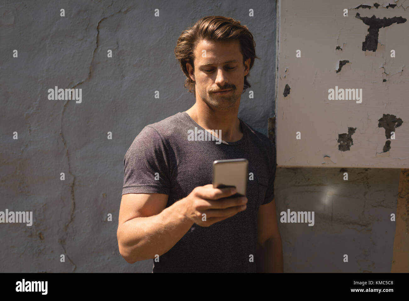 Man using mobile phone against wall Stock Photo - Alamy