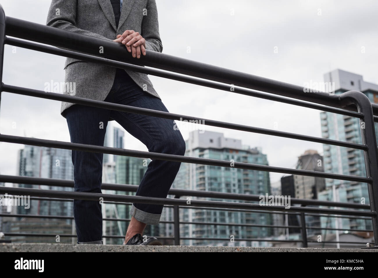 Businessman standing near railing Stock Photo - Alamy