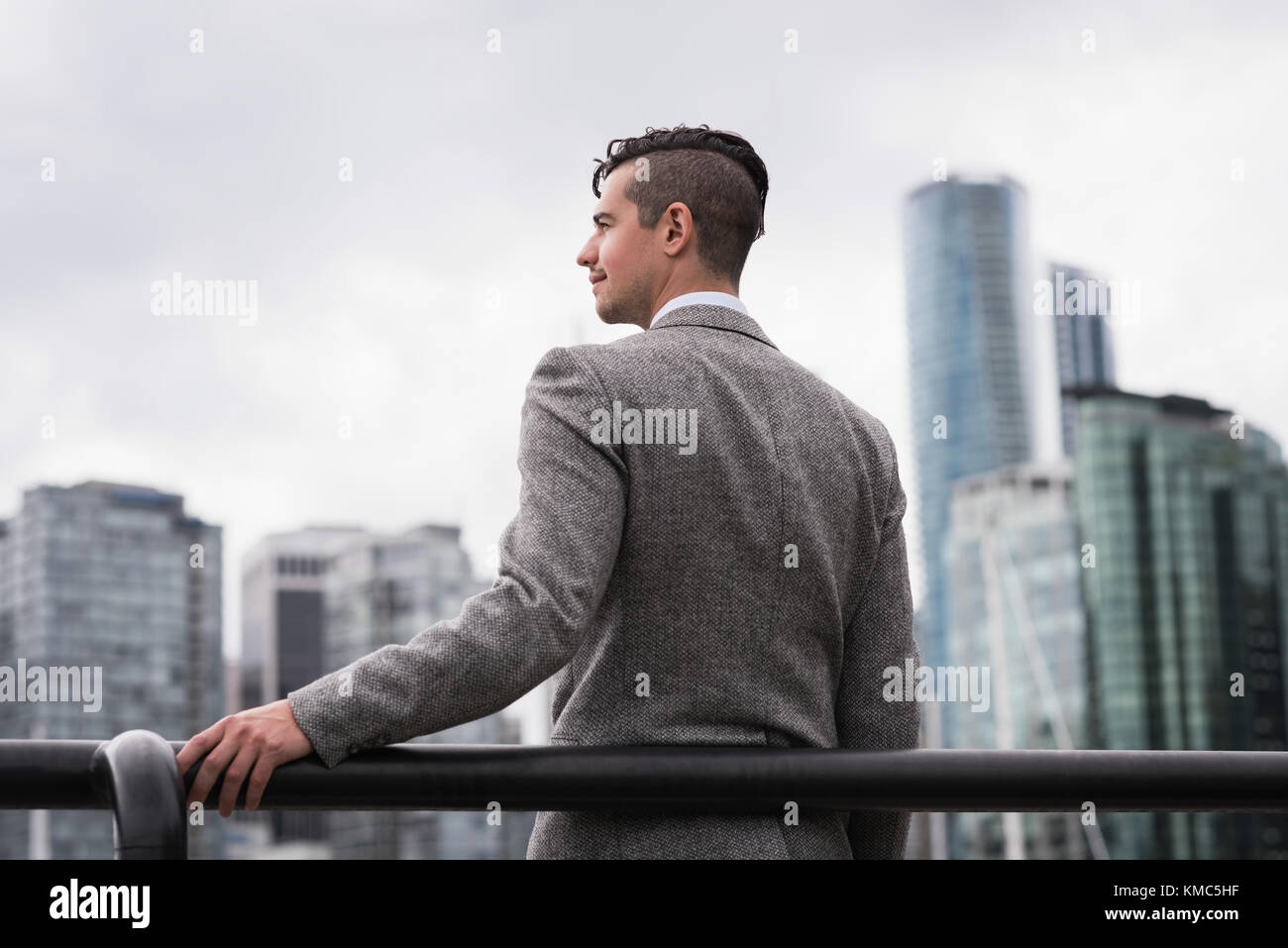 Businessman standing near railing Stock Photo - Alamy