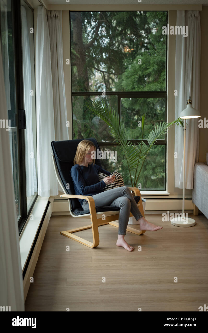 Woman using mobile phone in living room Stock Photo - Alamy