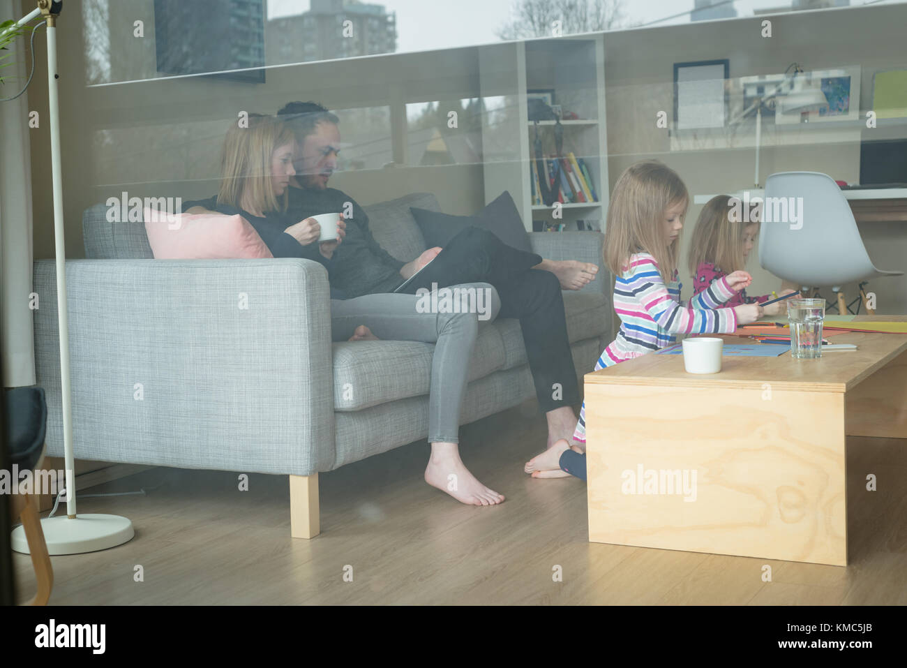 Parents using digital tablet while children drawing a sketch in living ...