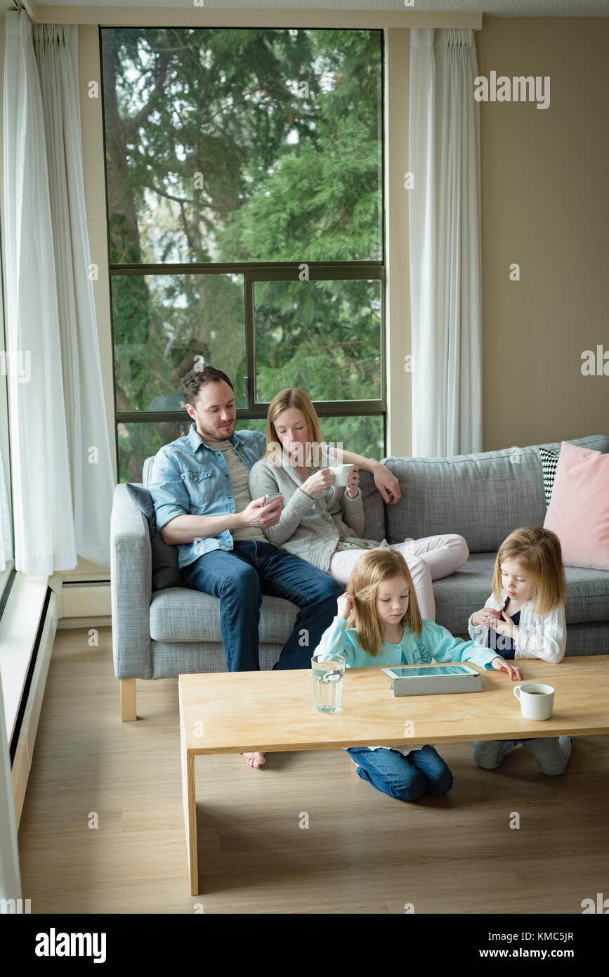 Parents using mobile phone while children using digital tablet Stock ...