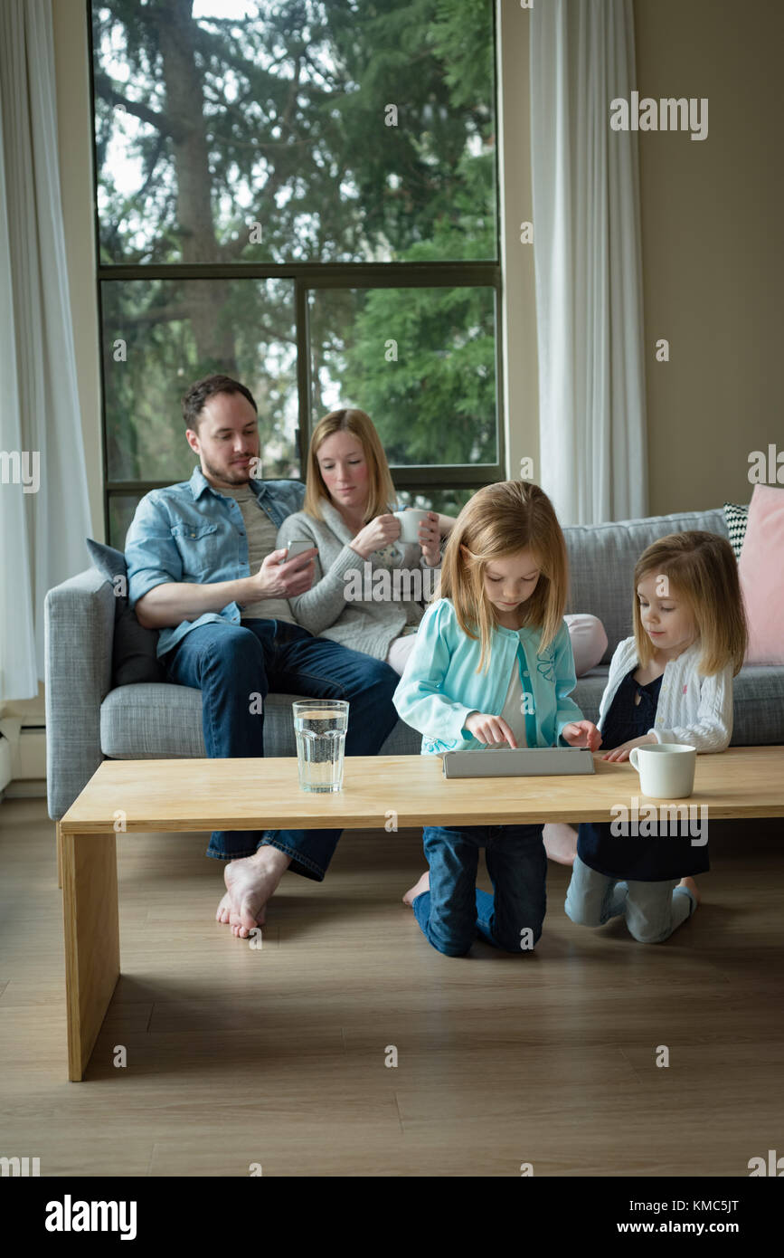 Parents using mobile phone while children using digital tablet Stock ...