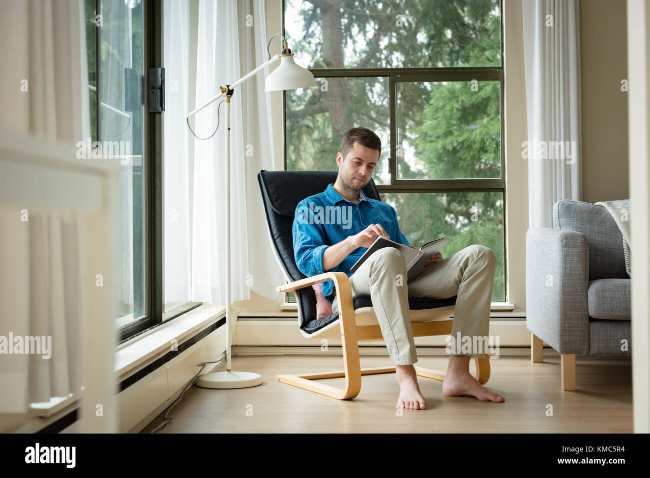 Man reading a book in living room Stock Photo - Alamy