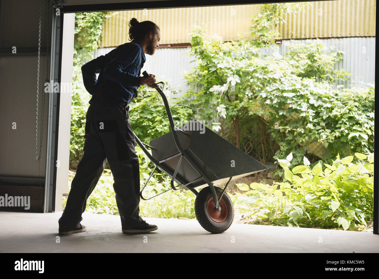 Mechanic using wheelbarrow Stock Photo - Alamy