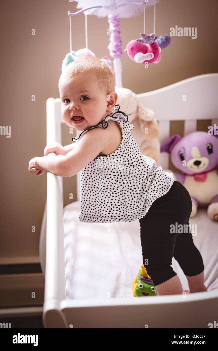 Cute girl standing in cot Stock Photo - Alamy