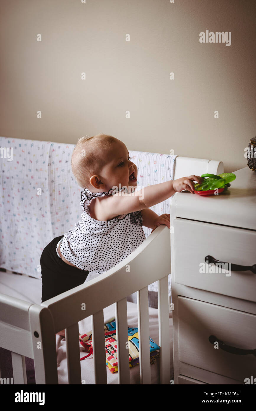 Cute girl trying to reach out the toy Stock Photo - Alamy