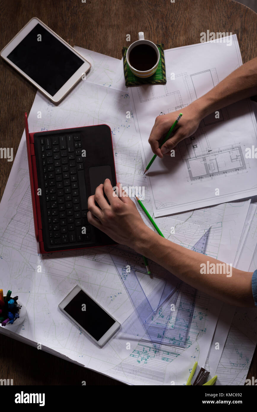 Male graphic designer working on laptop and blueprint Stock Photo - Alamy