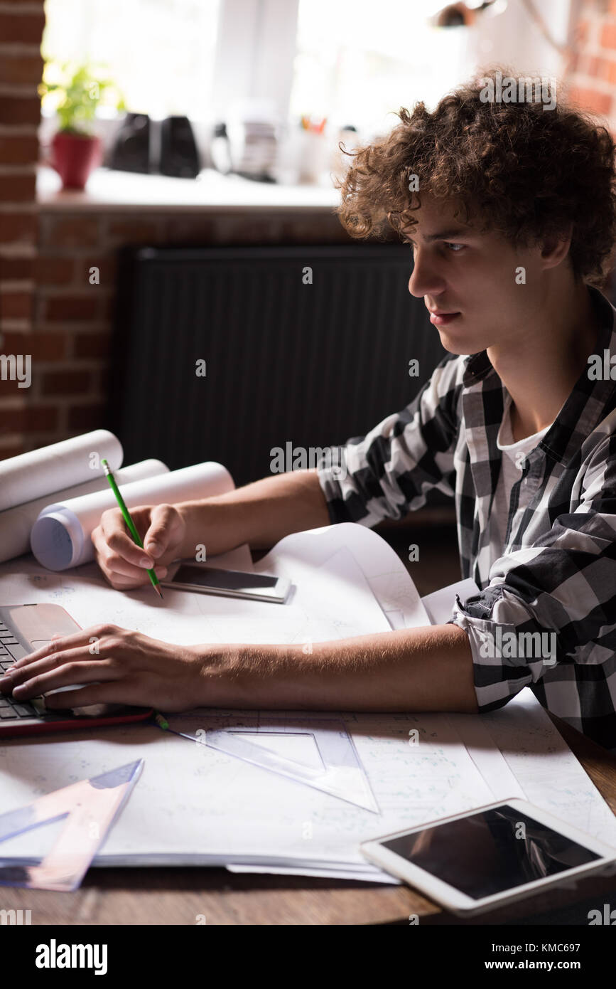 Male graphic designer working on laptop and blueprint Stock Photo - Alamy
