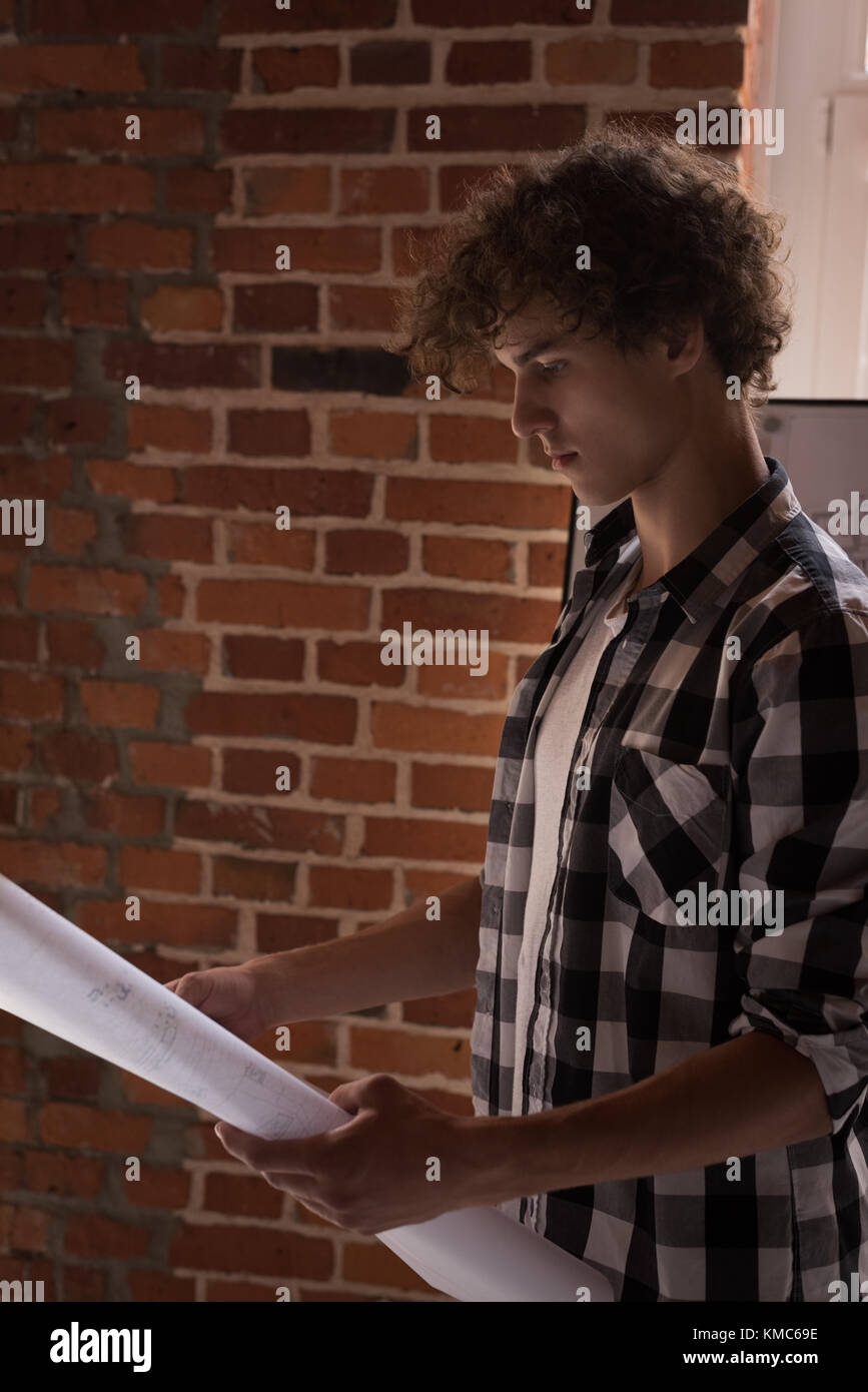 Male graphic designer looking at blueprint Stock Photo - Alamy