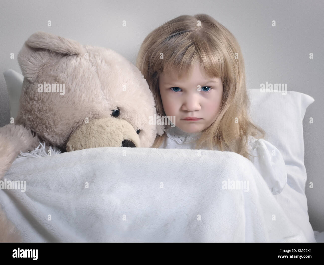 Sad little girl with plush bear in bed. Portrait of a distressed child ...