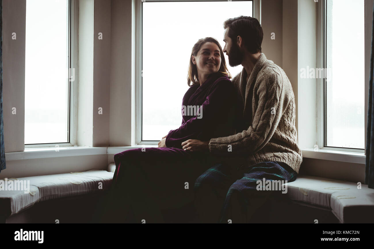 Happy couple sitting near window Stock Photo - Alamy