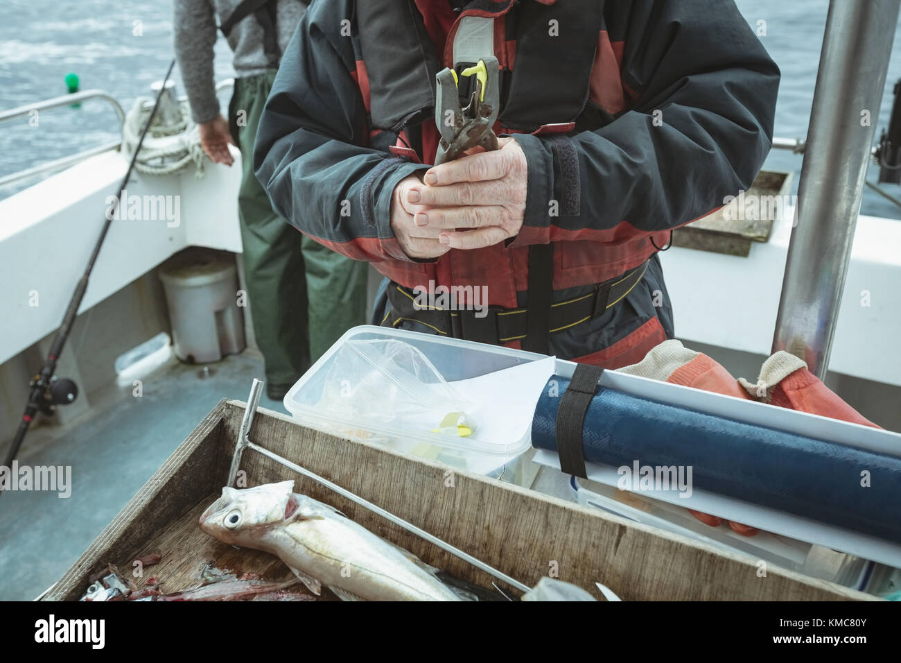 Fisherman pressing tag with hand tool Stock Photo - Alamy