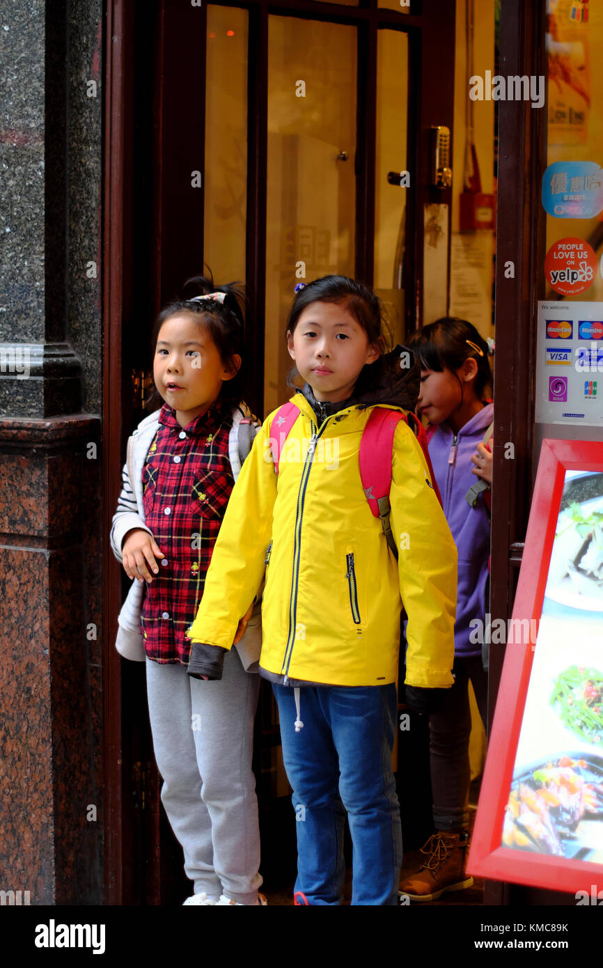 Chinese school children standing in doorway of shop in Chinatown, Soho ...