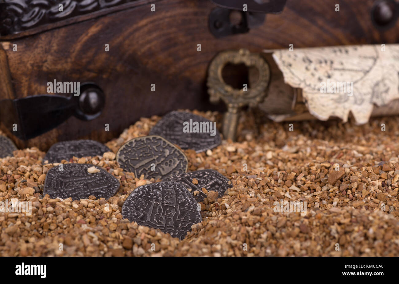 Old coins on sand with treasure map and chest in background Stock Photo ...