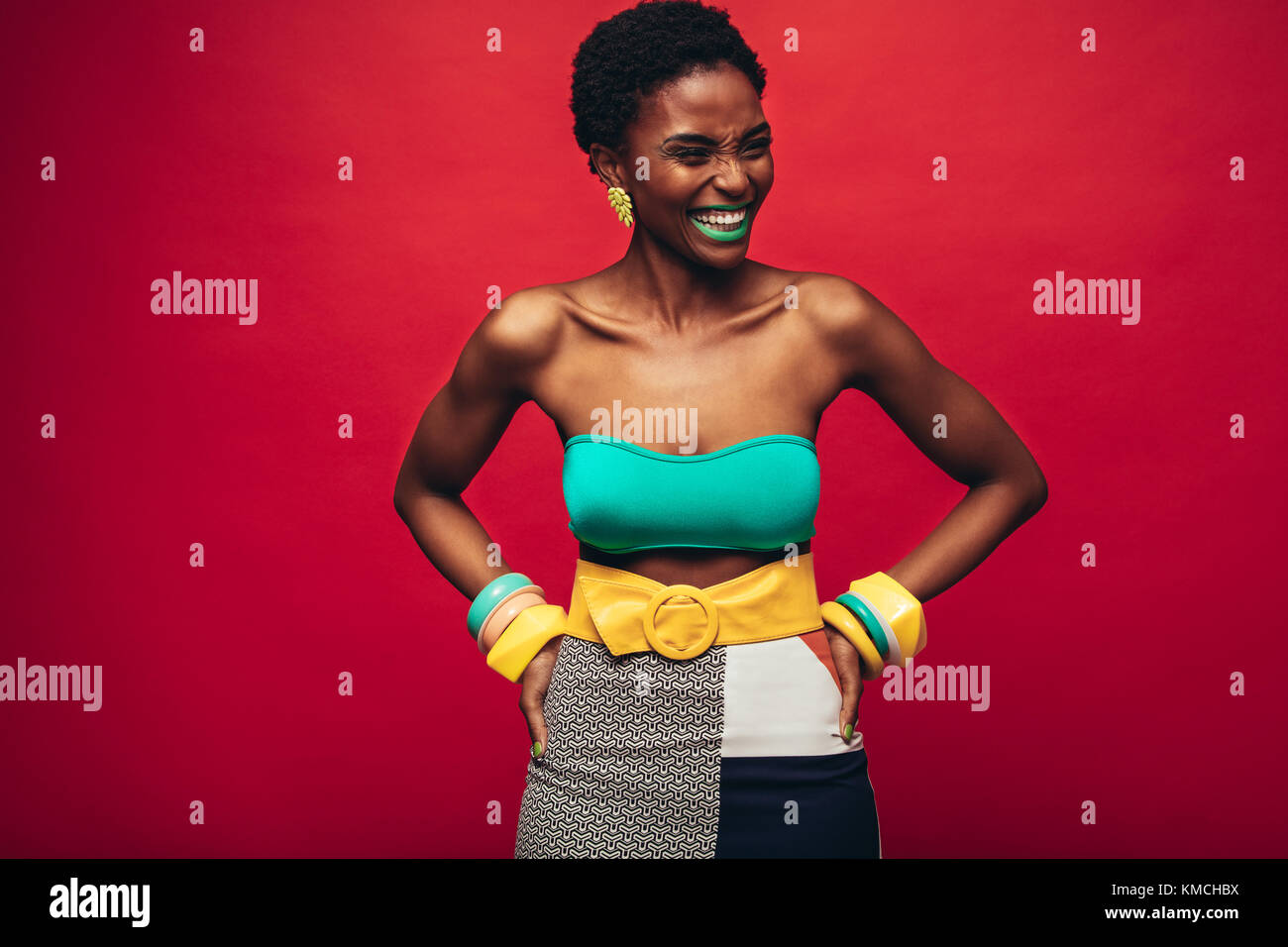 African woman in stylish outfit standing over red background. African ...