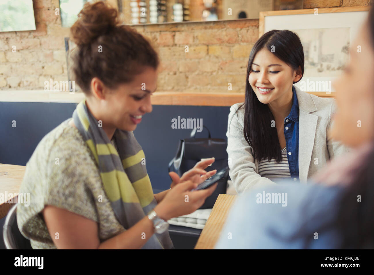 Female friends texting with cell phone in cafe Stock Photo - Alamy