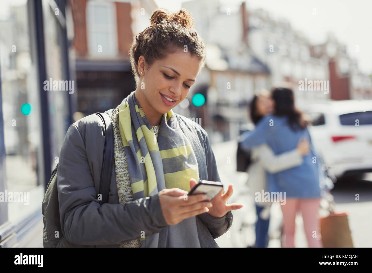 Young woman texting on sunny urban street Stock Photo - Alamy
