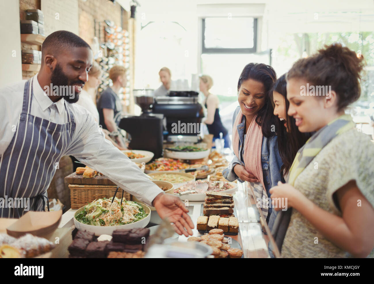 Male worker helping female customers in cafe Stock Photo - Alamy