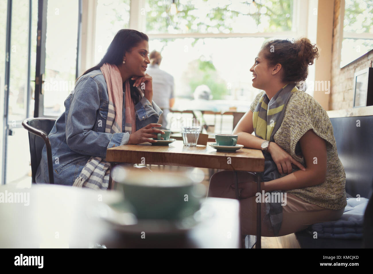 Women friends drinking coffee and talking at cafe table Stock Photo - Alamy