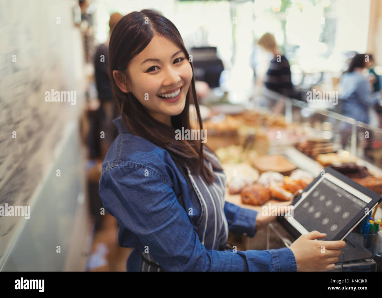 Portrait smiling, confident female cashier at cash register in cafe ...