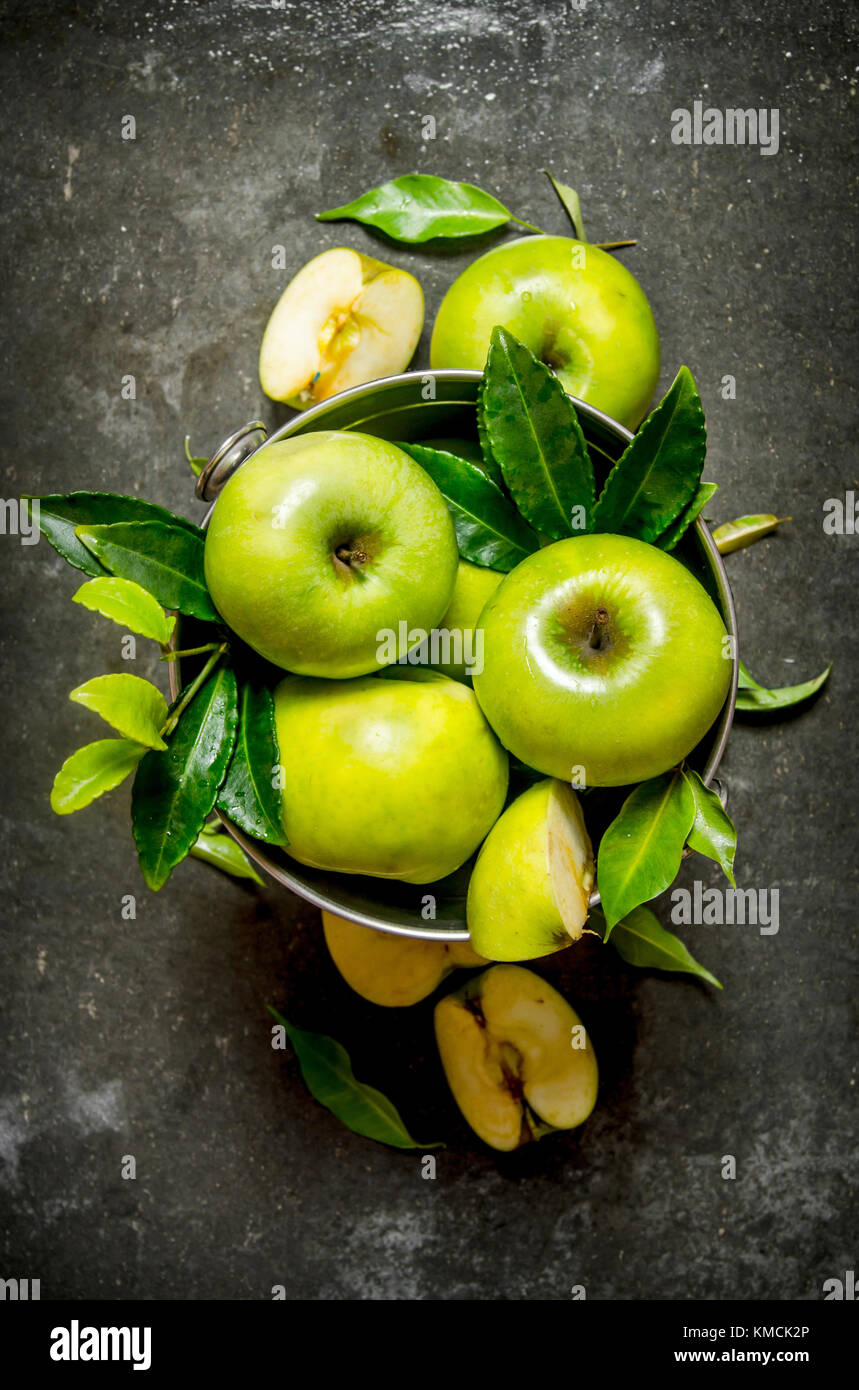 Green apples with leaves in the bucket. On rustic stone background. Top ...