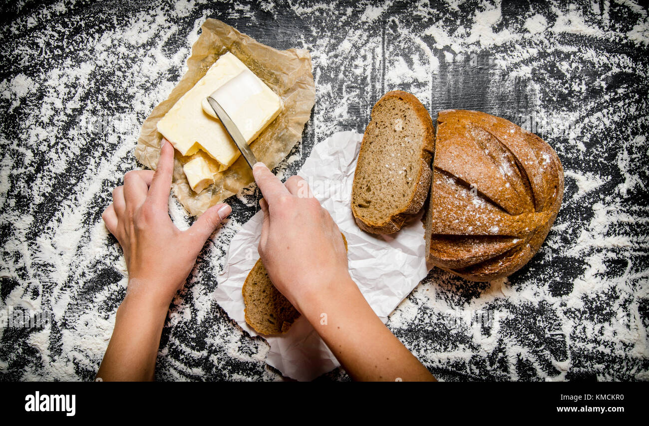 The buttering of bread with butter on a Board with flour. Top view ...