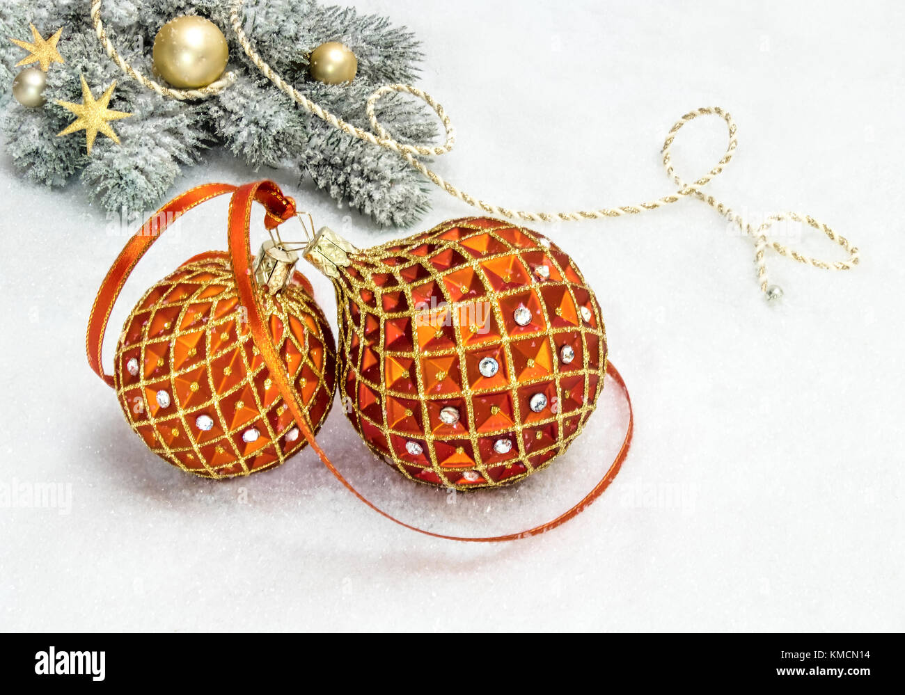 Two red Christmas baubles on snow with decorated Christmas tree twigs ...