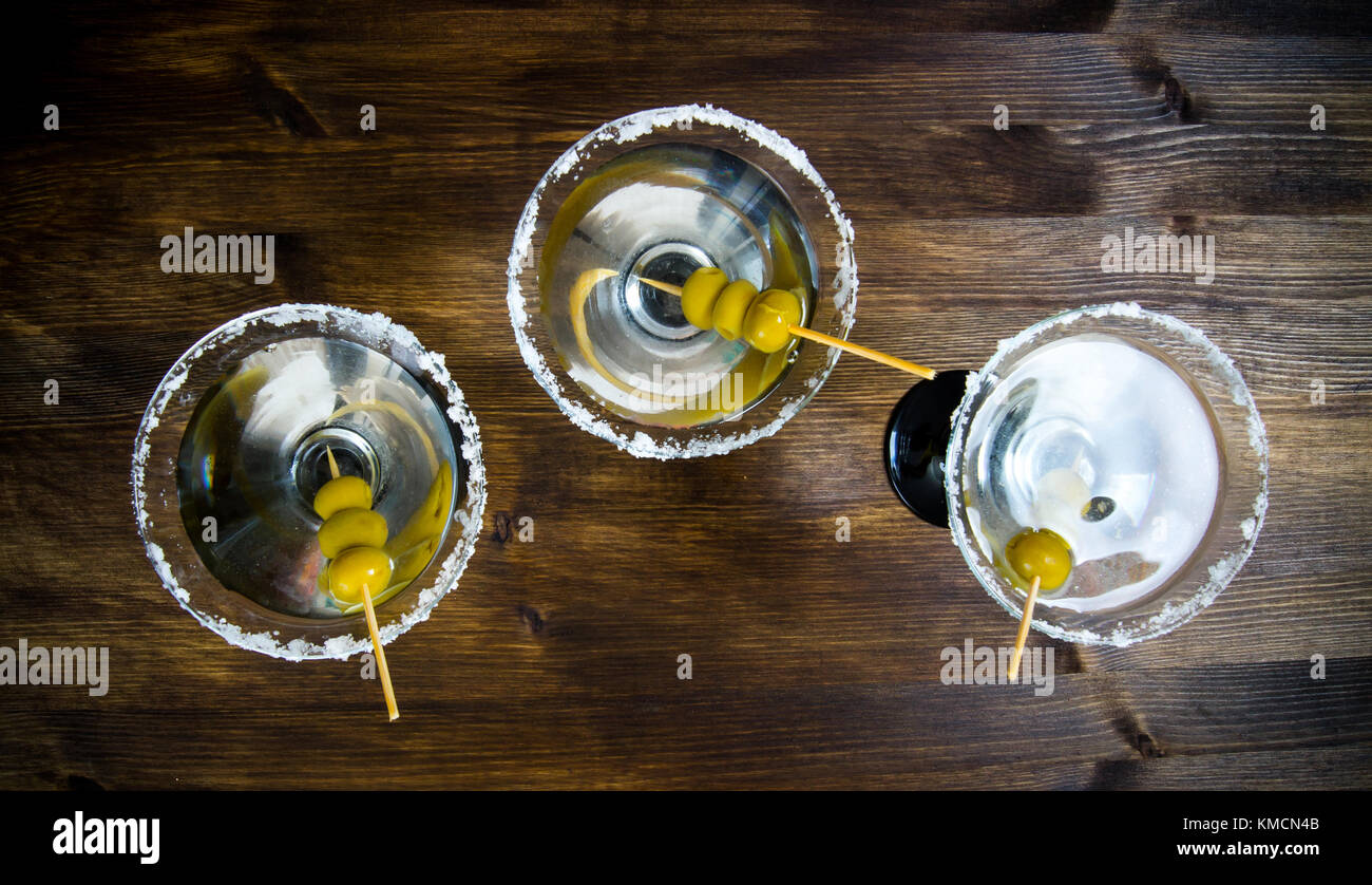 Drink martini. Three Martini with olives on a wooden table. Top view ...