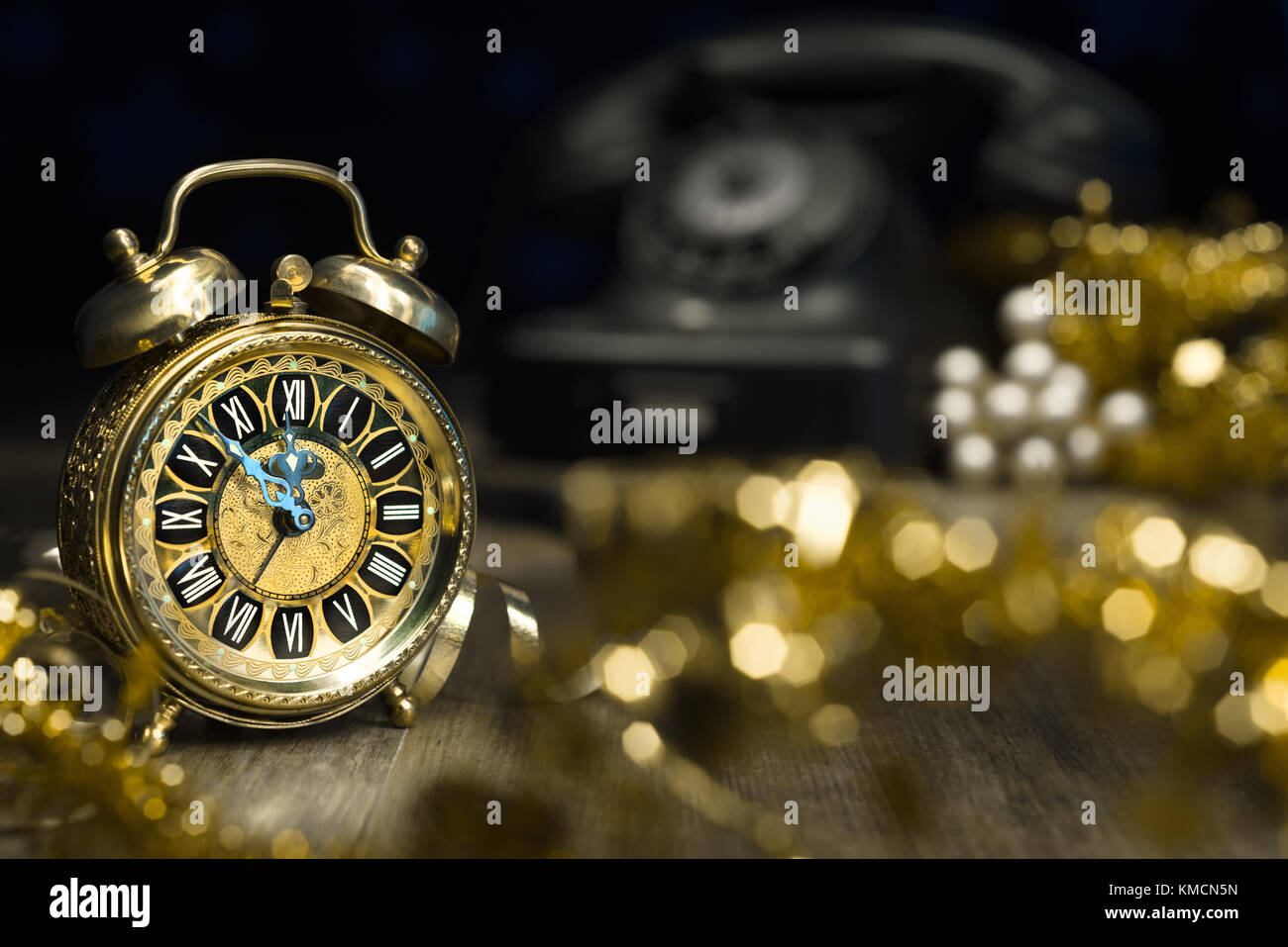 Vintage alarm clock showing five to midnight and an old phone. Happy ...