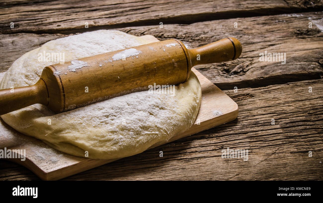 Preparation of the dough. The prepared dough with a rolling pin. On a ...