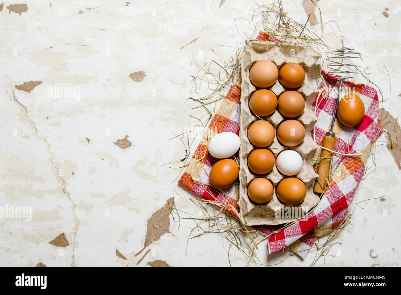 The cassette with eggs, hay and whisk on the fabric. On rustic ...