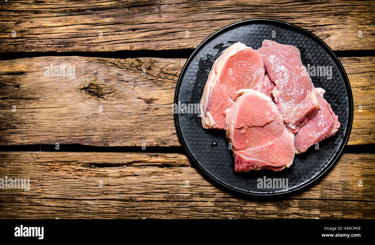 Fresh raw meat on a stand. On the wooden background. Free space for ...