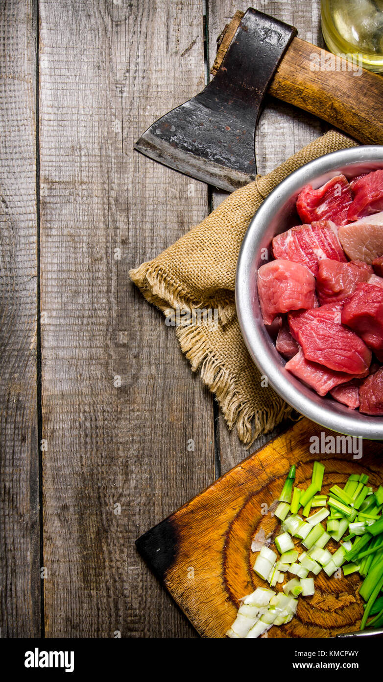 Chopped raw meat with fresh onions and an axe on an old fabric. On a ...