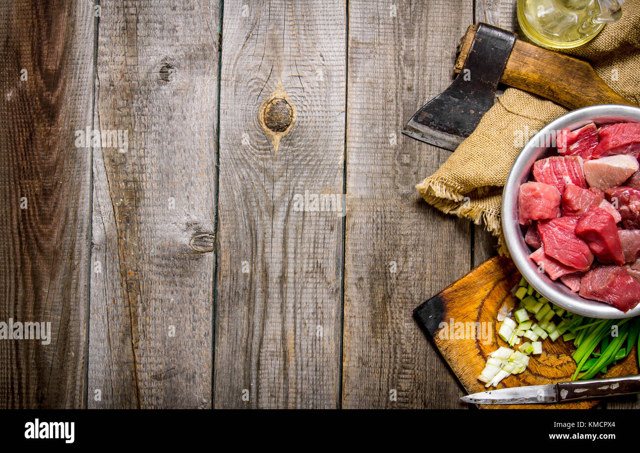 Chopped raw meat with fresh onions and an axe on an old fabric. On a ...