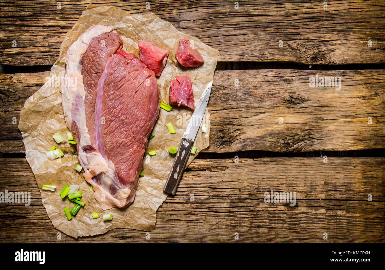 Fresh raw meat with a butcher knife. On wooden background. Free space ...