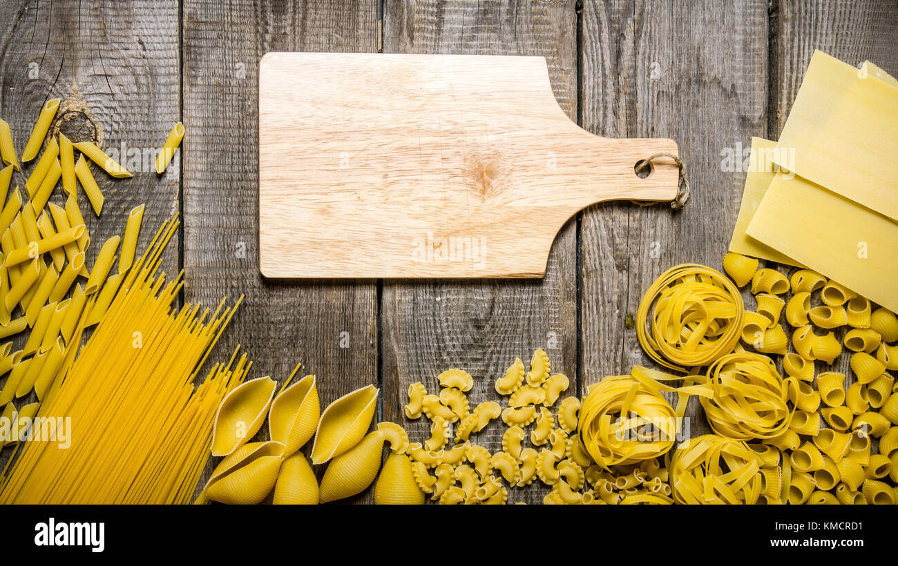 Mixed types of pasta and spaghetti with an empty plate. On wooden ...